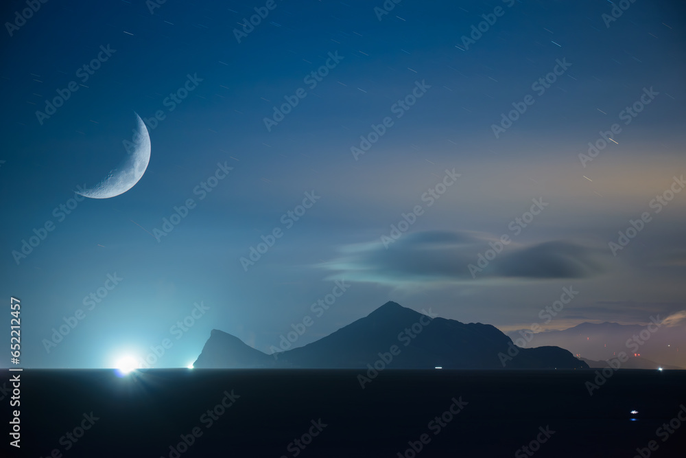 A poetic half-moon montage of fishing boat lights on the shore of an ...