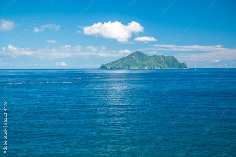 Blue sea and blue sky with changing white clouds. Small islands and ...