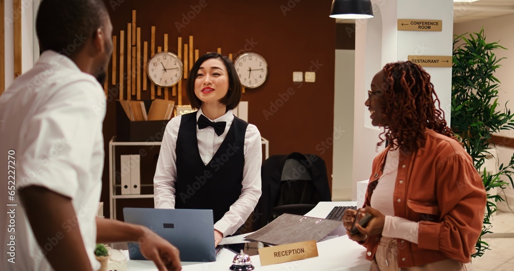 Friendly receptionist presenting holiday package options to african ...