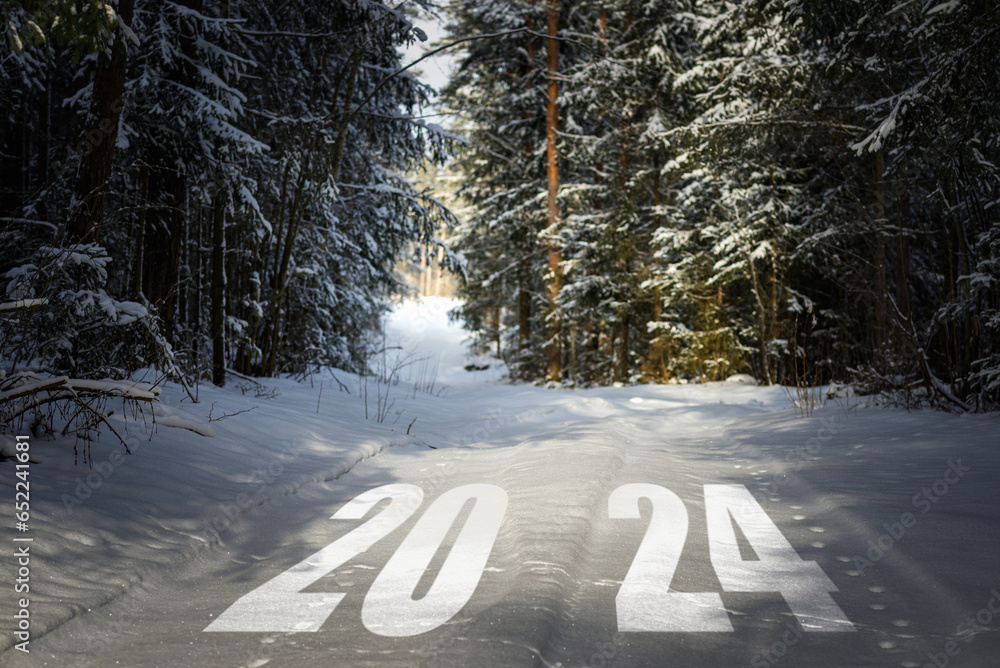2024 New year inscription on the snow covered road in winter forest ...
