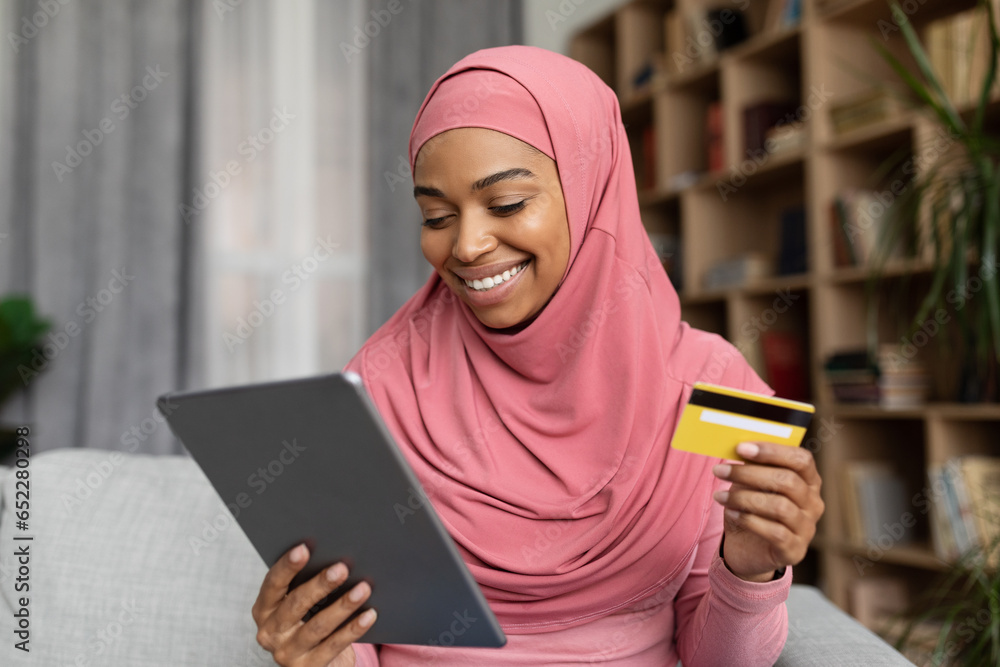 Virtual easy banking. Happy young black muslim woman in hijab sitting ...