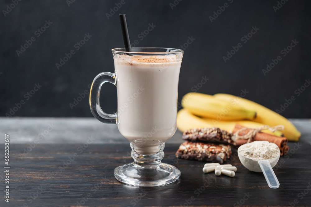 Glass of protein milkshake drink with straw and scoop of whey protein ...