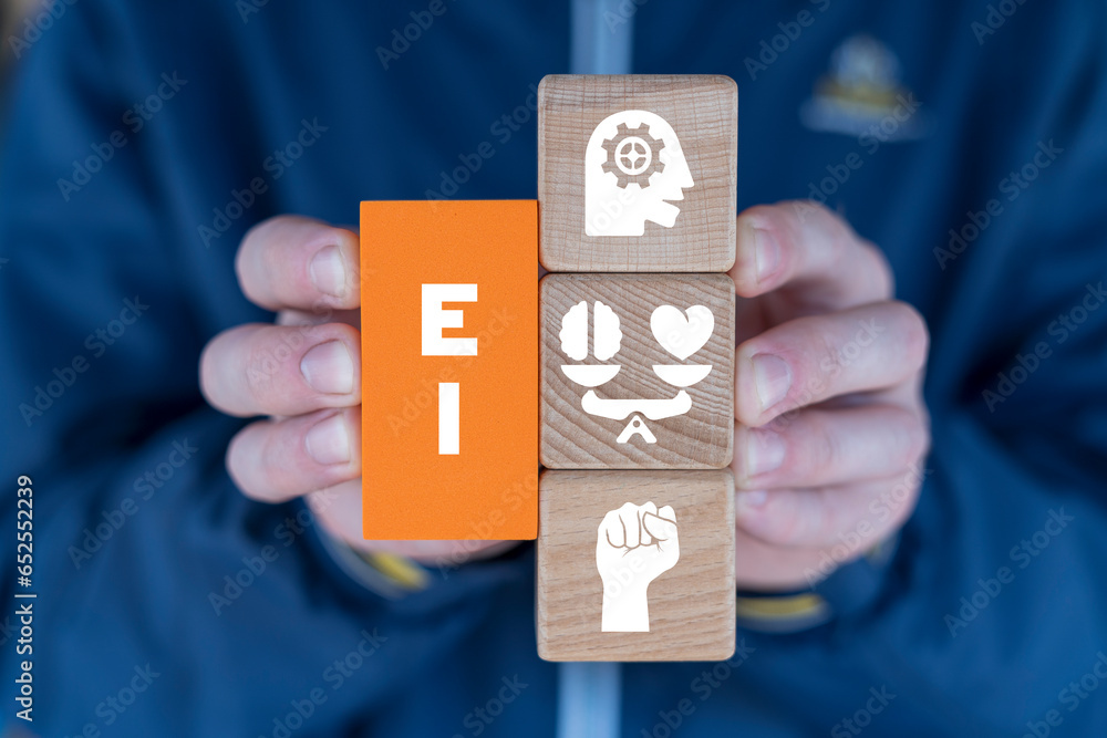 Hands holding colorful blcoks with icons and abbreviation: EI. Emotional and intelligence ...