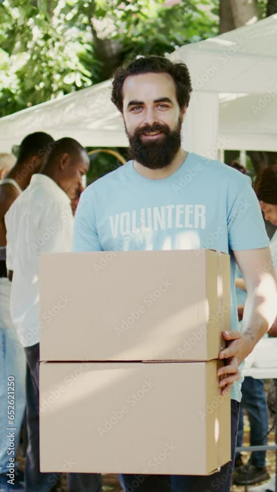 Vertical video At a food drive, kind young guy holding non-perishable ...