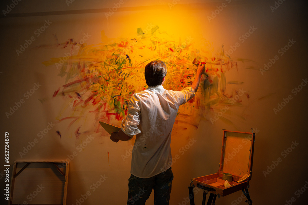 Artist man painting a contemporary modern artwork on the large wall ...