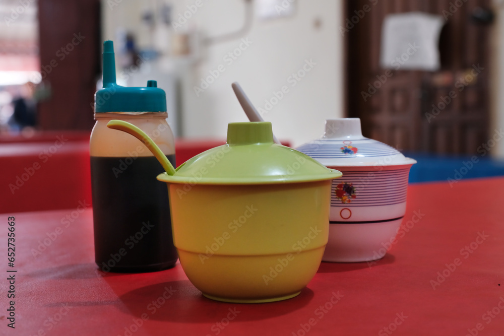 plastic containers for soya sauce, hot chilli and salt on red table of ...