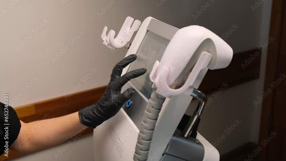 The hand of a cosmetologist, wearing black latex gloves, touches the ...