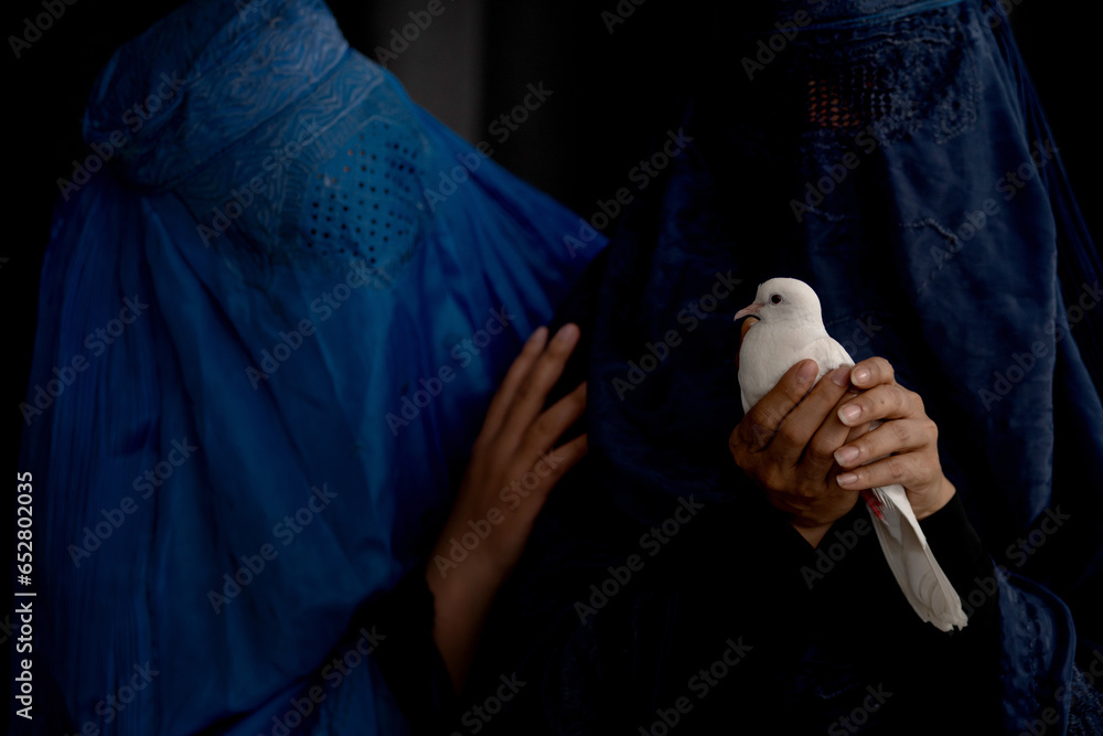 Two Muslim women in traditional burqa hold white doves in their hands ...