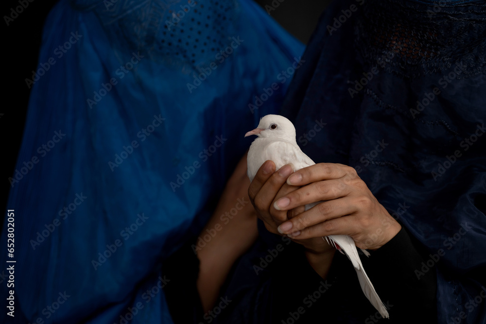 Two Muslim women in traditional burqa hold white doves in their hands ...