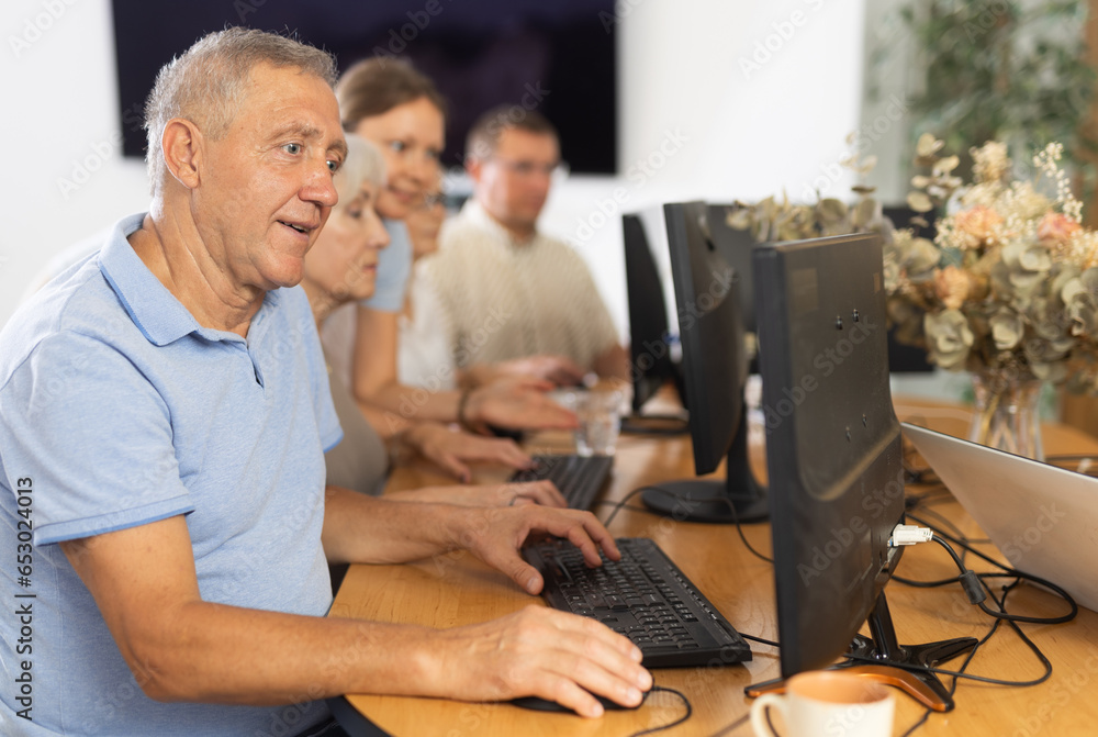Elderly man learns how to work with computer in group at computer ...