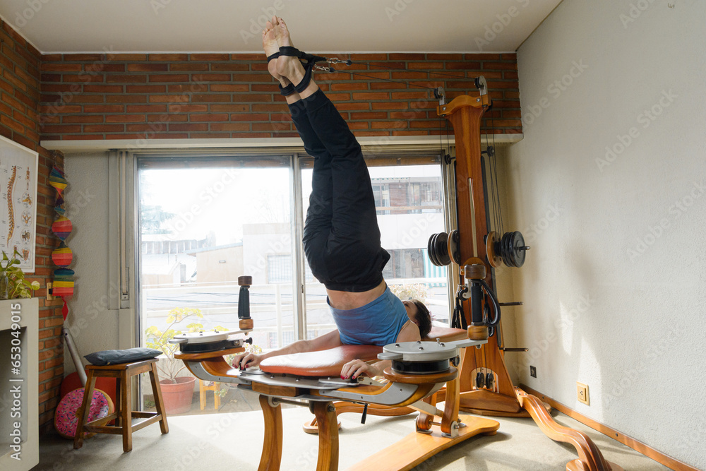 Caucasian woman lying on back on exercise machine with pulleys and ...