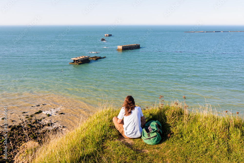 A young woman sitting at the Cap Manvieux in Tracy-sur-Mer, observes ...