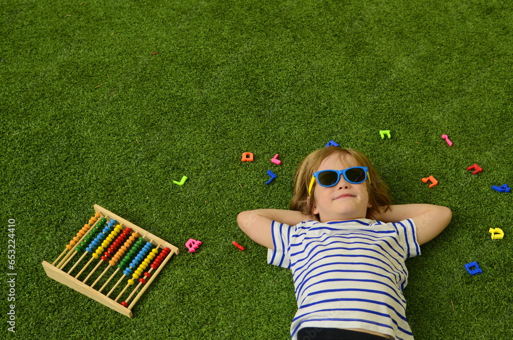 Hebrew alphabet. The boy lies on the grass, letters lie around his head ...