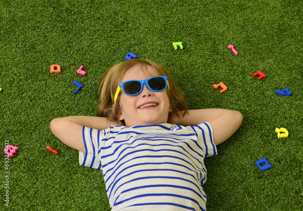 Hebrew alphabet. The boy lies on the grass, letters lie around his head ...