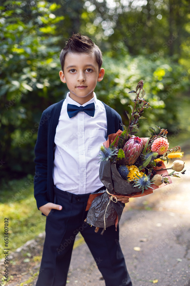 portrait first-grader boy in a uniform with a bow tie holding a bouquet ...