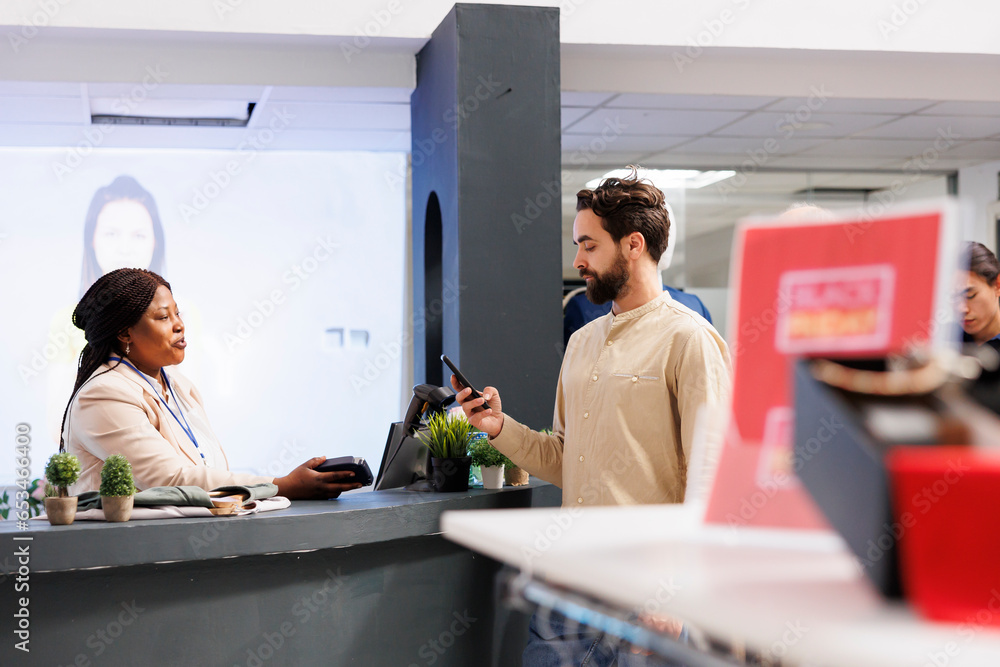Male customer holding smartphone making contactless payment while ...