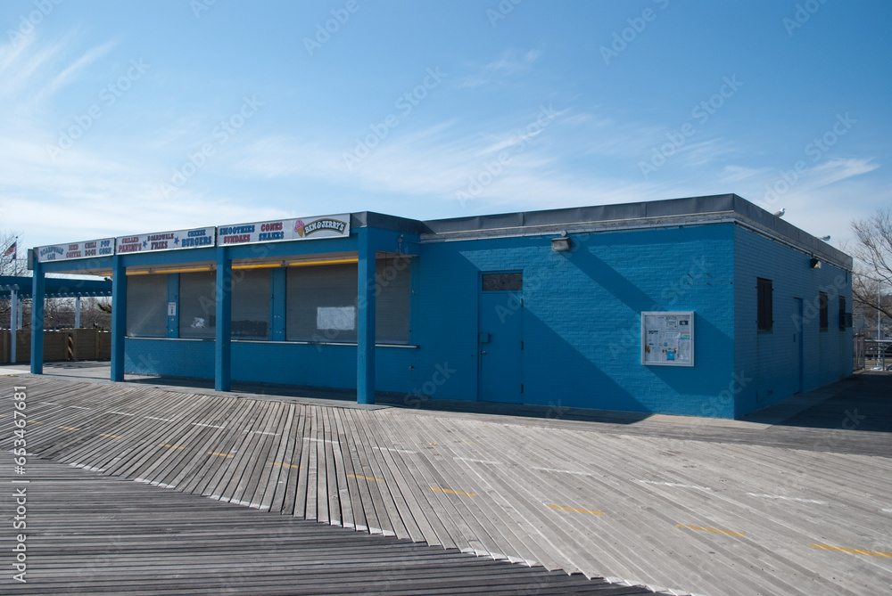 Empty ocean boardwalk with a closed storefront that sells hot dogs, ice ...