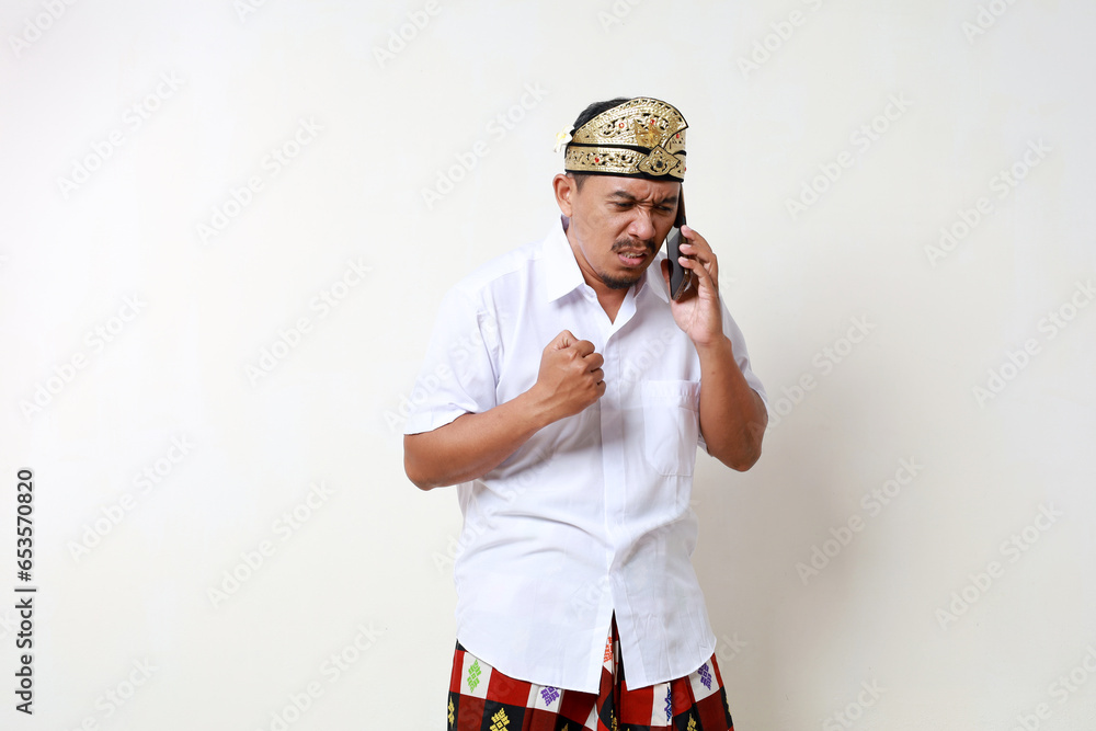 Angry Asian man in balinese traditional costume standing while talking ...