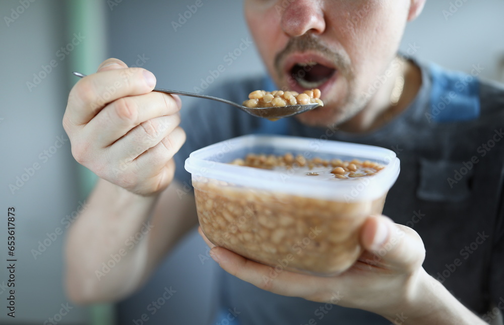 Close-up of male worker eating tinned baked beans in tomato sauce from ...