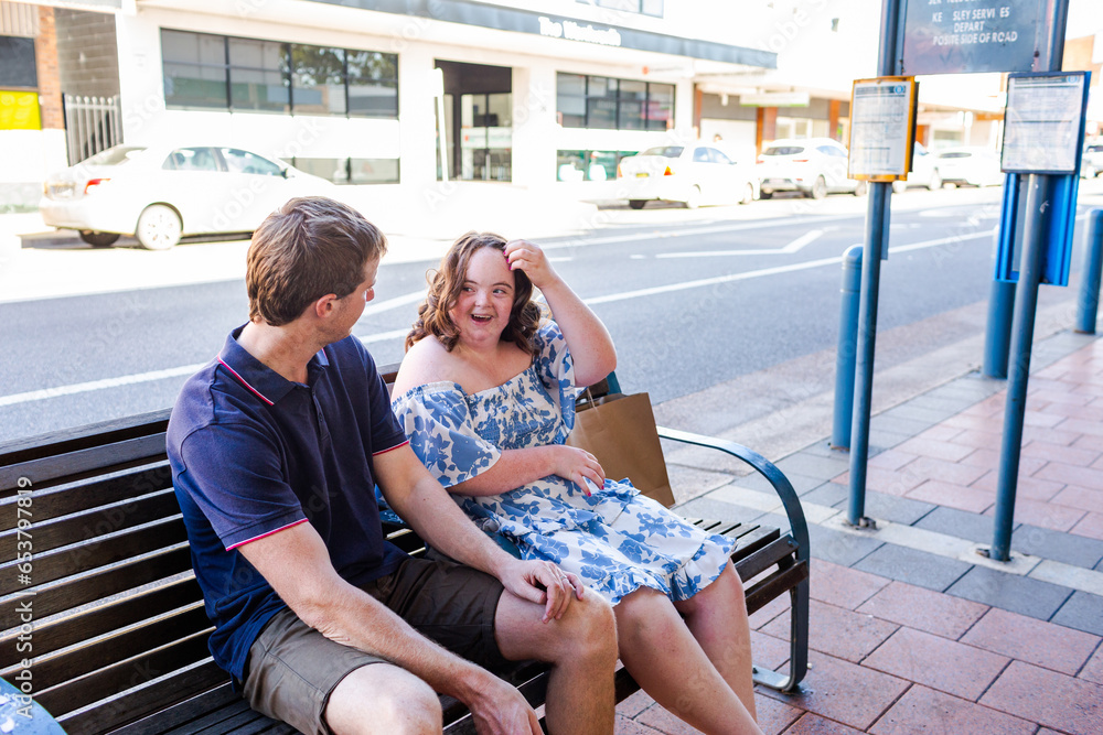 Girl with down syndrome chatting with disability worker at bus stop ...