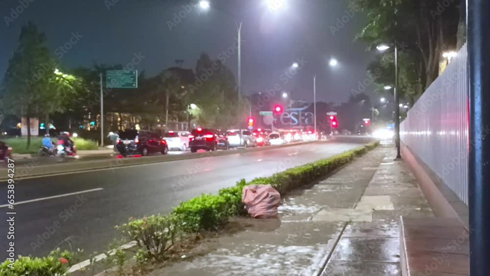 Vehicles at a traffic light on an urban road at night. The queue of ...