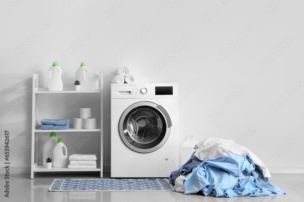 Washing machine, shelving unit and pile of dirty laundry near white ...