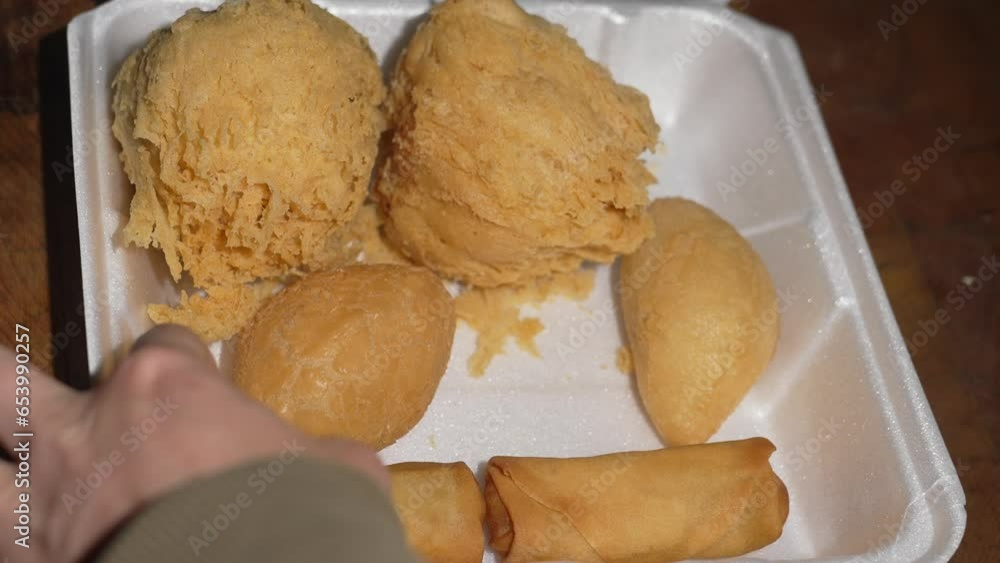 This video shows a hands grabbing fried dim sum from styrofoam take out ...