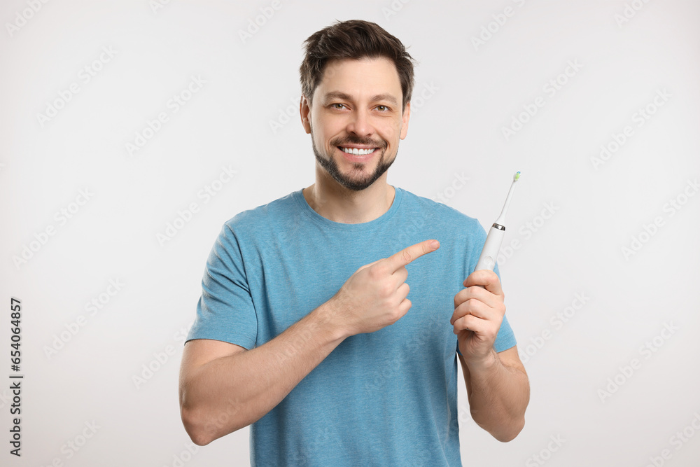 Happy man holding electric toothbrush on white background Stock Photo ...