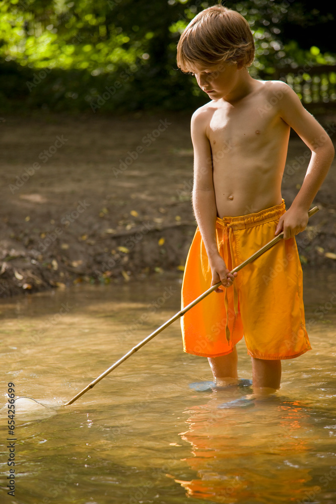 Young boy fishing in a river with fishing net Stock Photo | Adobe Stock