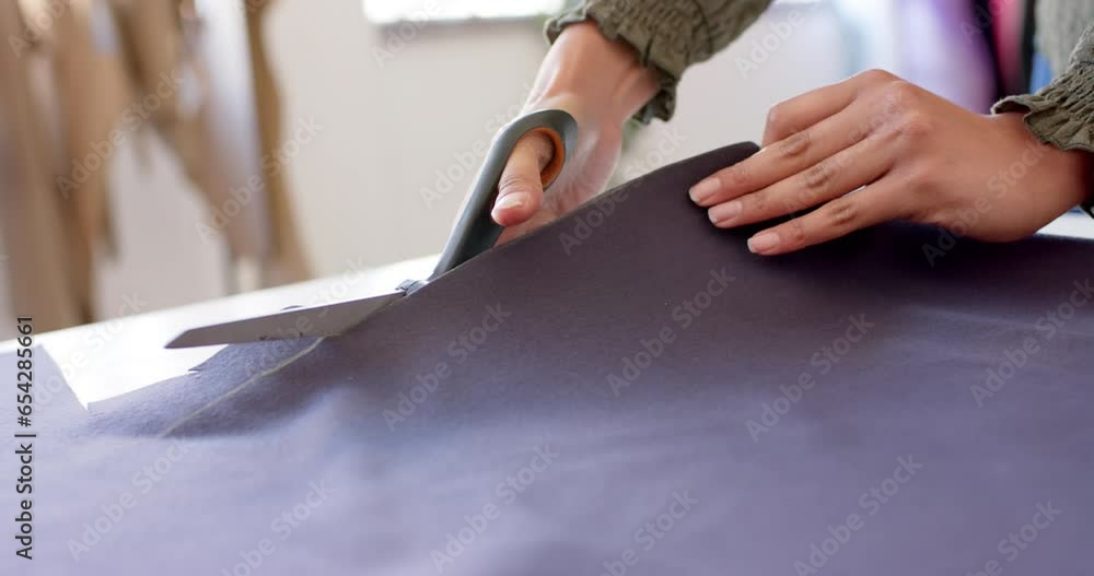 Hands of biracial female fashion designer cutting cloth with fabric ...