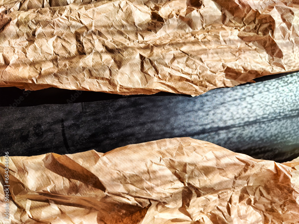 Heavily crumpled textured kraft paper with a black smooth insert in ...