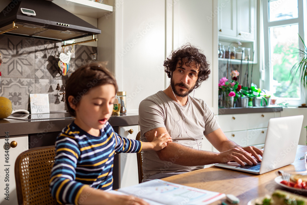 Young boy asking his father a question about his homework in the ...