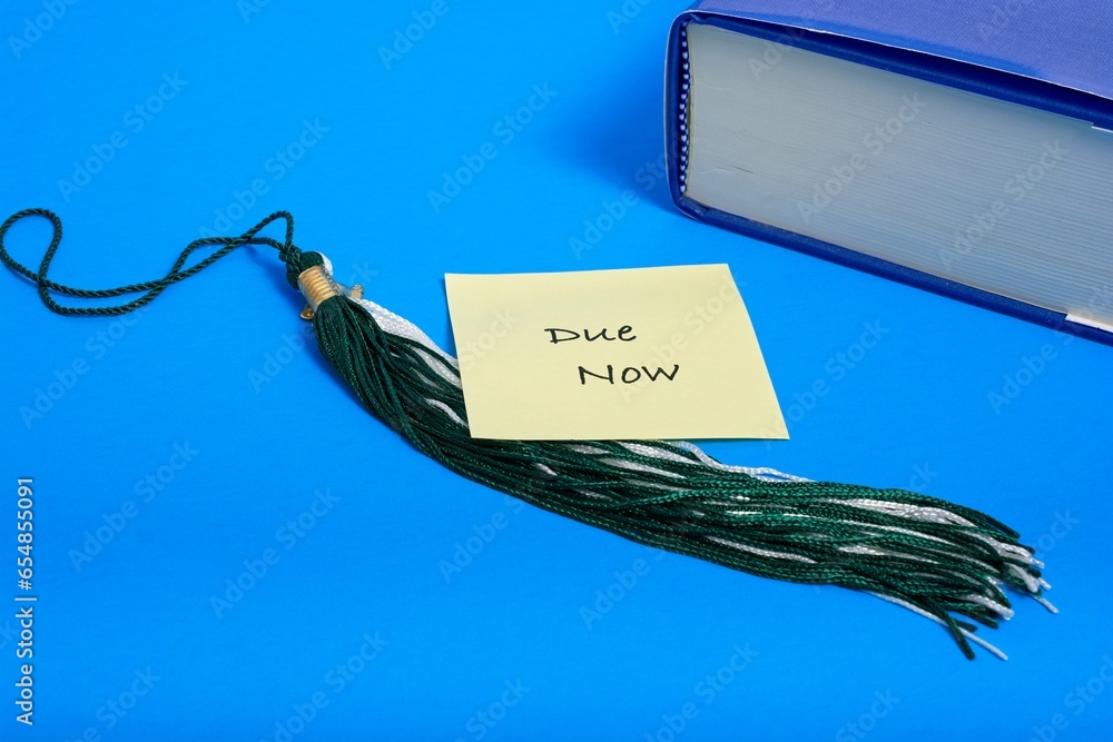 Debt reminder slip labeled ‘Due Now’ affixed to graduation cap tassel ...