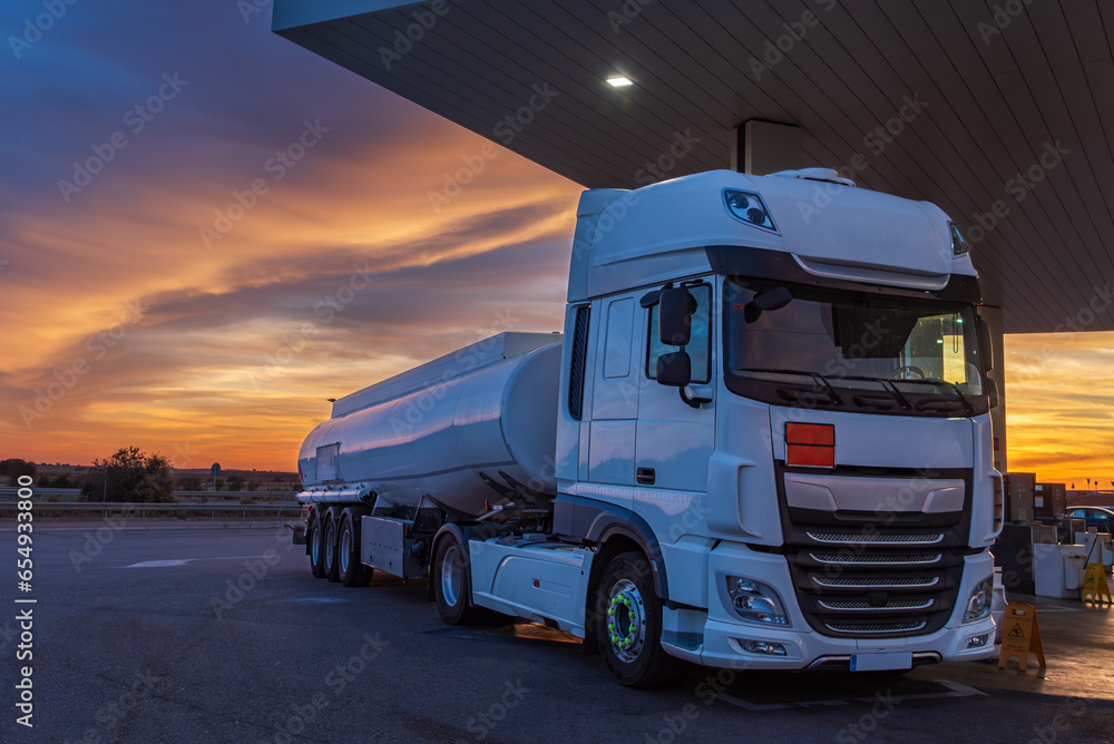 Fuel tanker truck refueling at a gas station under a dramatic sky ...