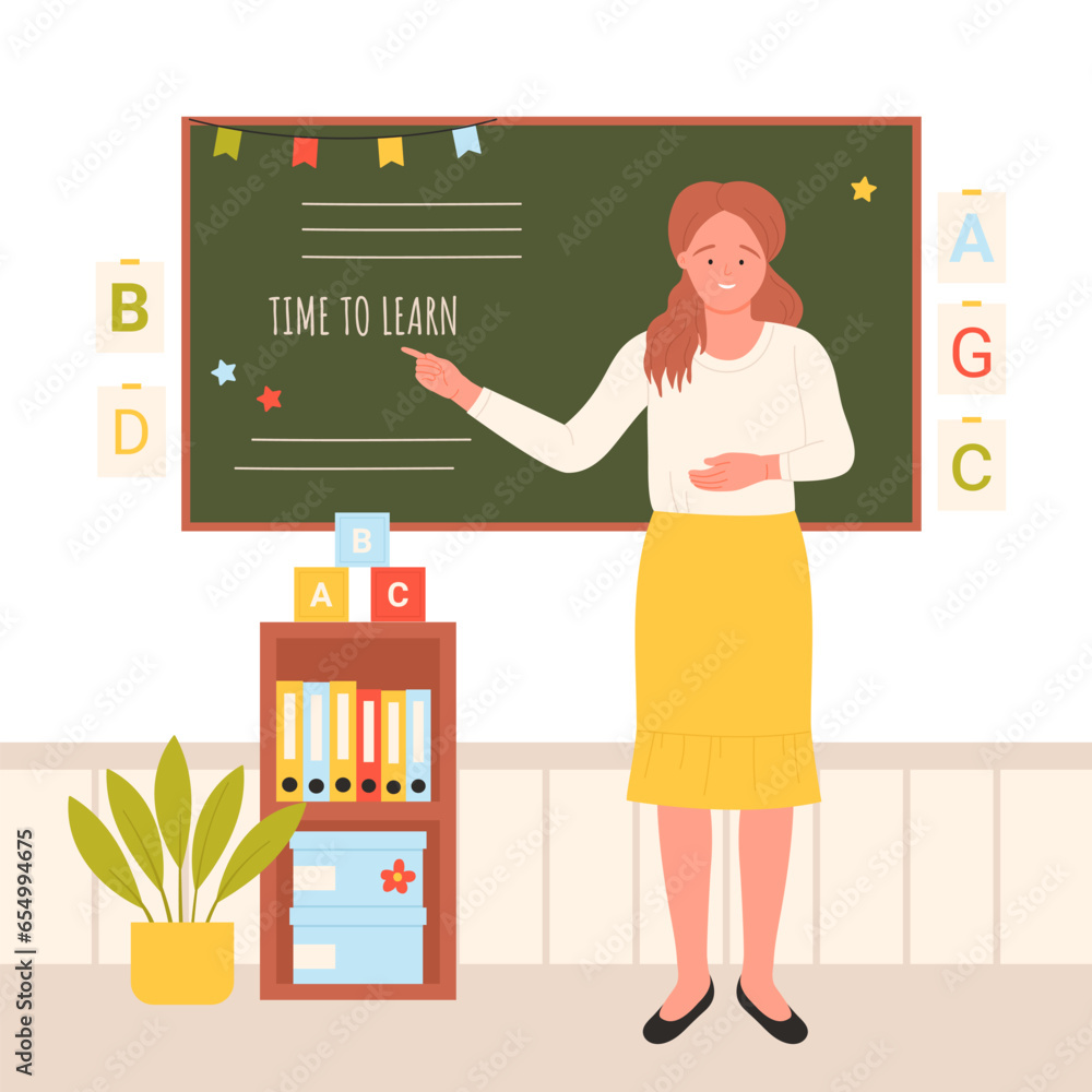 Primary school teacher standing at board in modern classroom interior ...