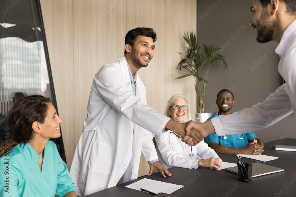 Happy young Indian male doctor giving handshake to cooperation partner ...