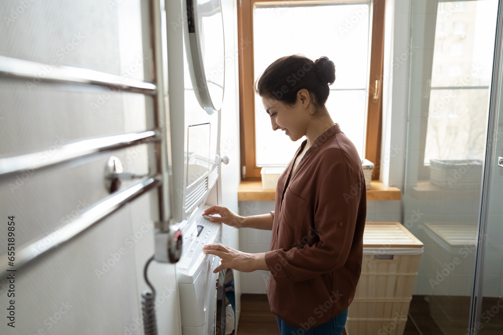 Smiling Indian woman turning on electronic washing machine, clothing ...