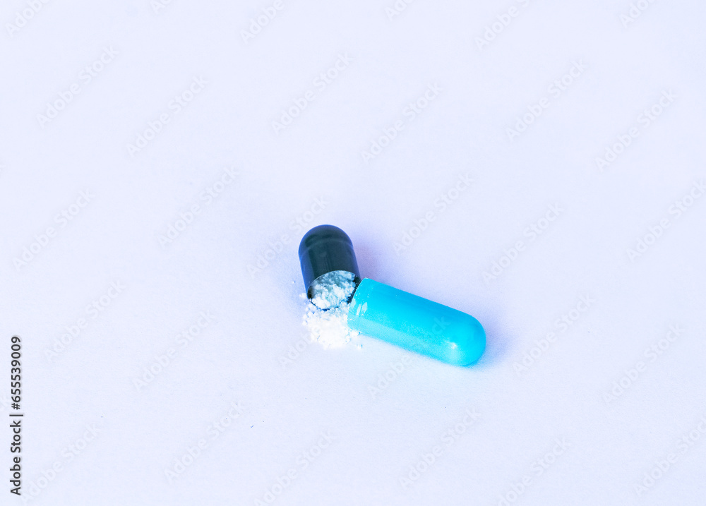 Drug capsule blue decisive damaged have white powder inside on white ...
