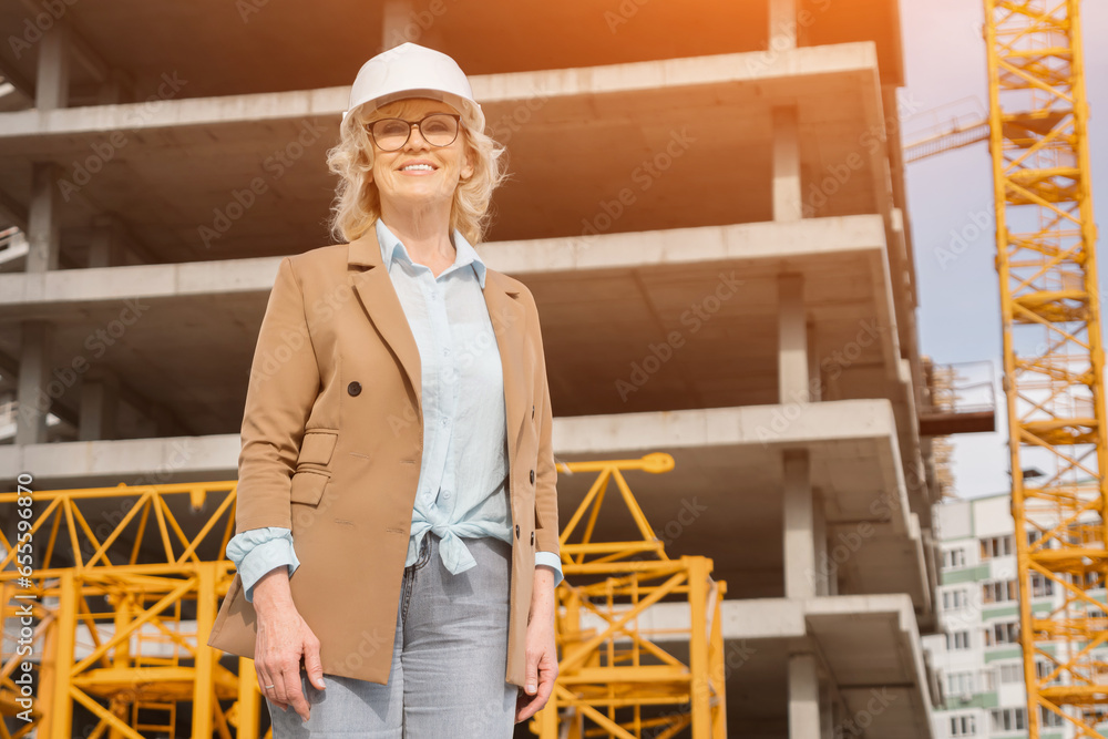Blonde businesswoman standing against construction site in front of ...