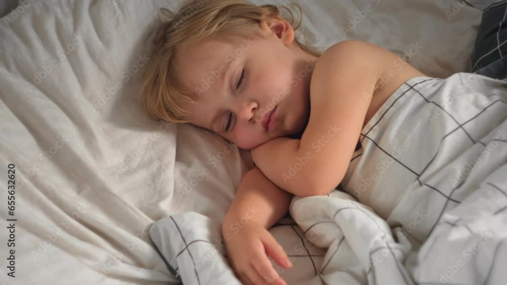 Peaceful adorable baby sleeping on a bed at home. Slumbering little child. Two years old girl ...