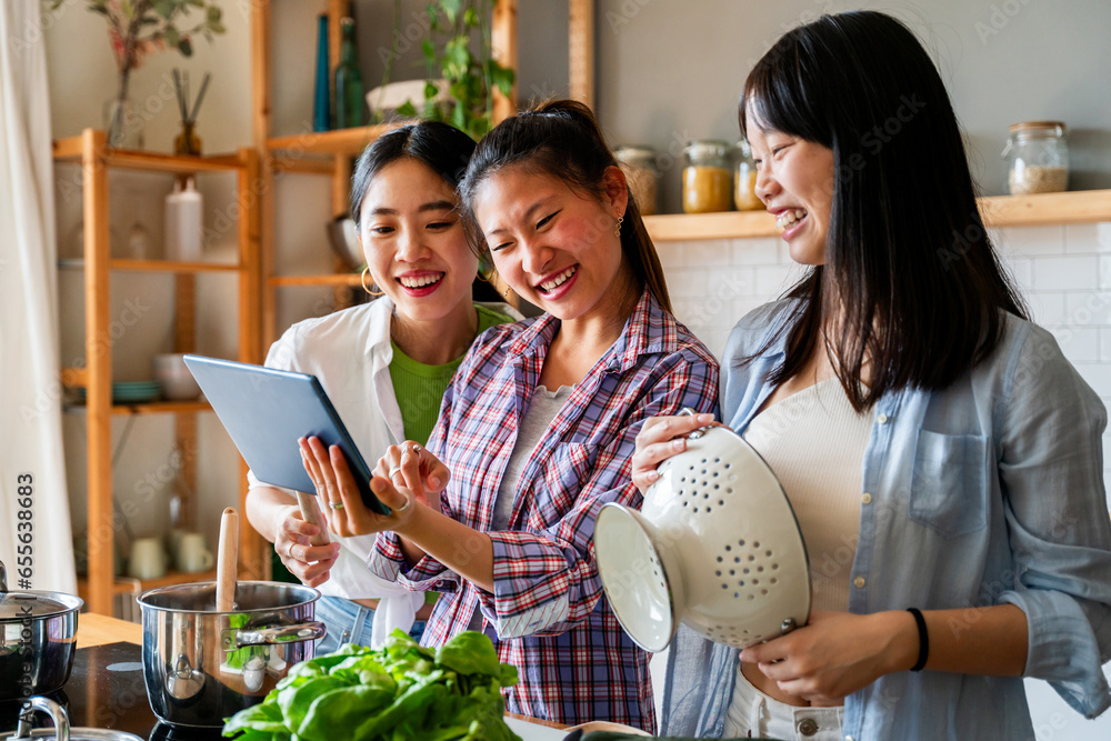 Happy beautiful chinese women friends bonding at home and cooking ...