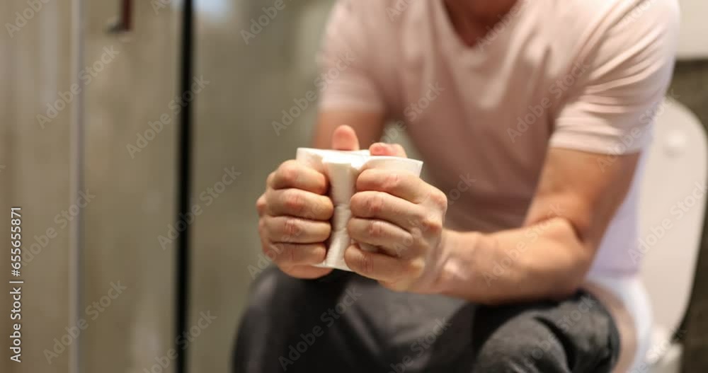 Man sits on toilet with toilet paper and suffers from constipation ...