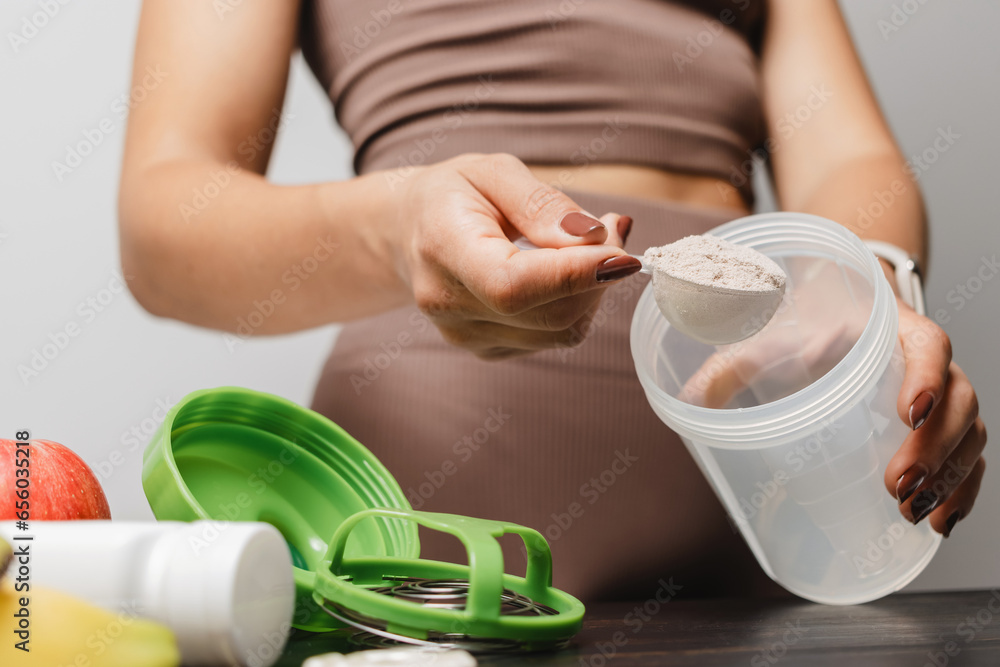 Athletic woman in sportswear with measuring spoon in her hand puts ...