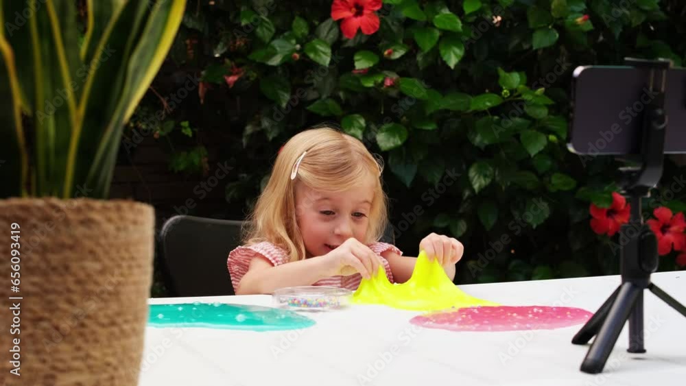 Laughing cute blonde caucasian girl with curly hair playing with slime ...