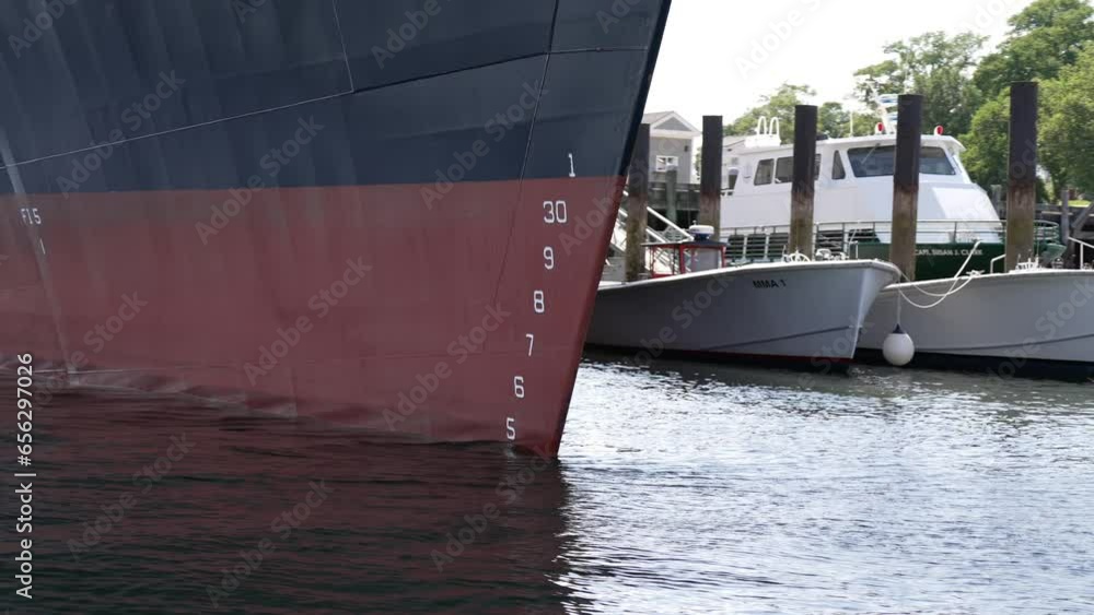 Numbers line up along bow of large ship docked in front of smaller ...