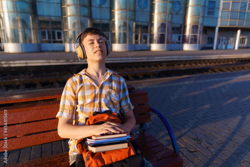 a student poses at a railway station, a boy is waiting for a train on ...