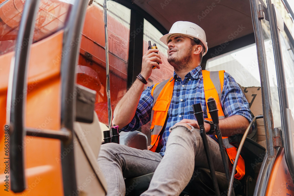Young man loader worker or a forklift driver in a container warehouse ...