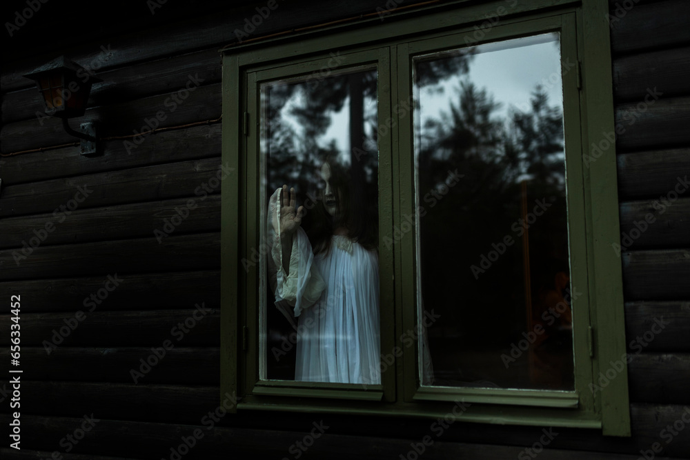 Female ghost looking through glass window of haunted cabin Stock Photo ...