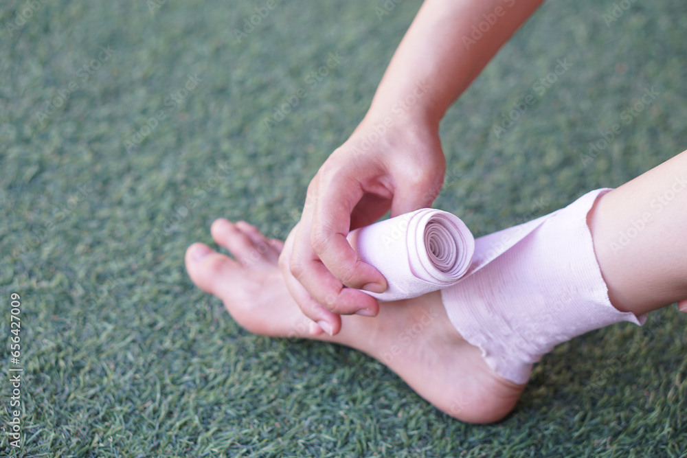 Close up hand is wrapping bandage on sprained ankle. Concept, first aid ...