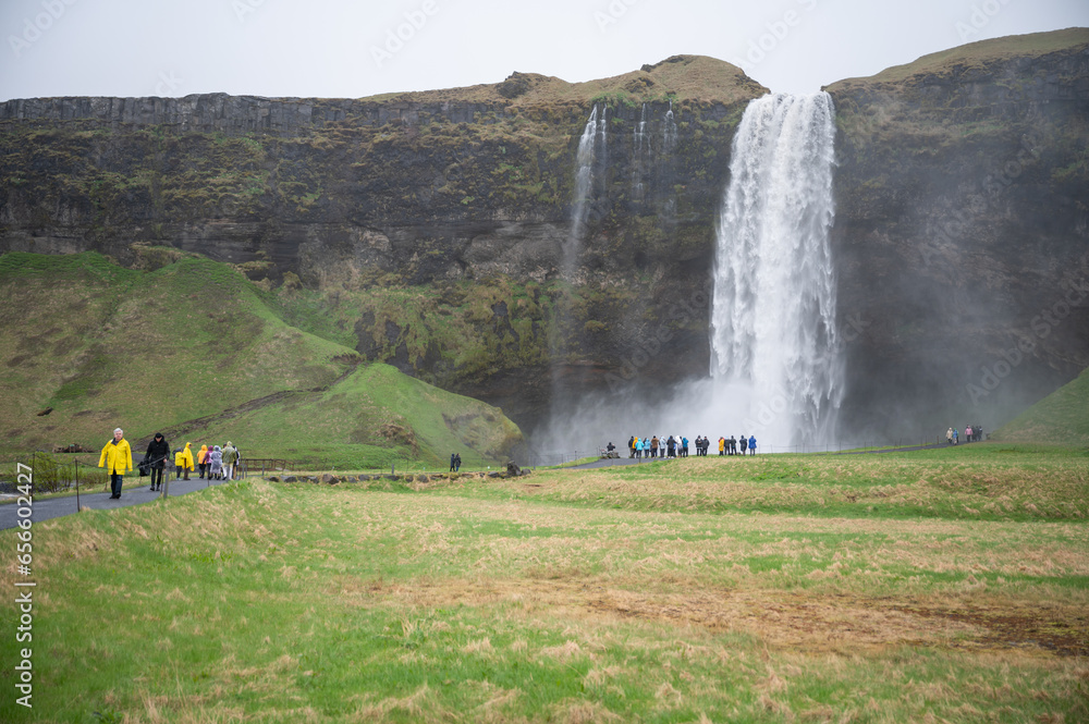 Seljalandsfoss Waterfall with walking path and tourist in rain voer in ...